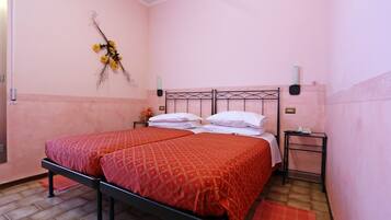Quarto com duas camas, paredes cor-de-rosa e um objeto decorativo na parede.