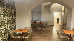 Uma sala de jantar com uma mesa comprida, várias cadeiras e um painel decorativo.