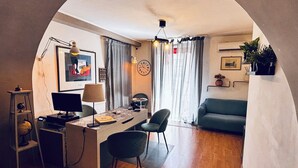 Uma sala de estar moderna com piso de madeira, uma escrivaninha com computador, uma cadeira, um sofá e uma área de jantar.