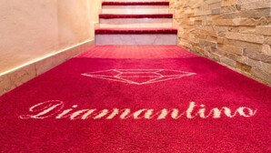Tapete vermelho com a inscrição 'Diamantino' que leva a uma escadaria.