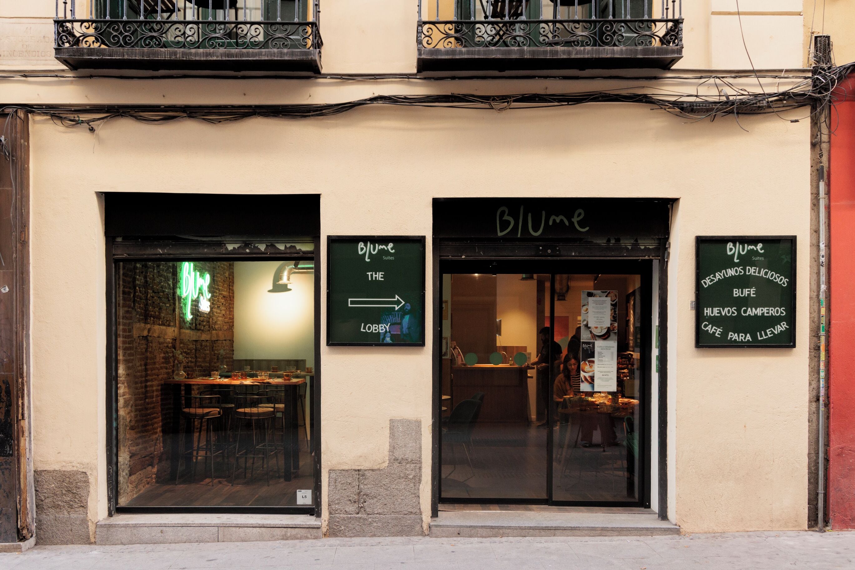 Um café com porta de vidro, um letreiro de neon e uma placa indicando a recepção.