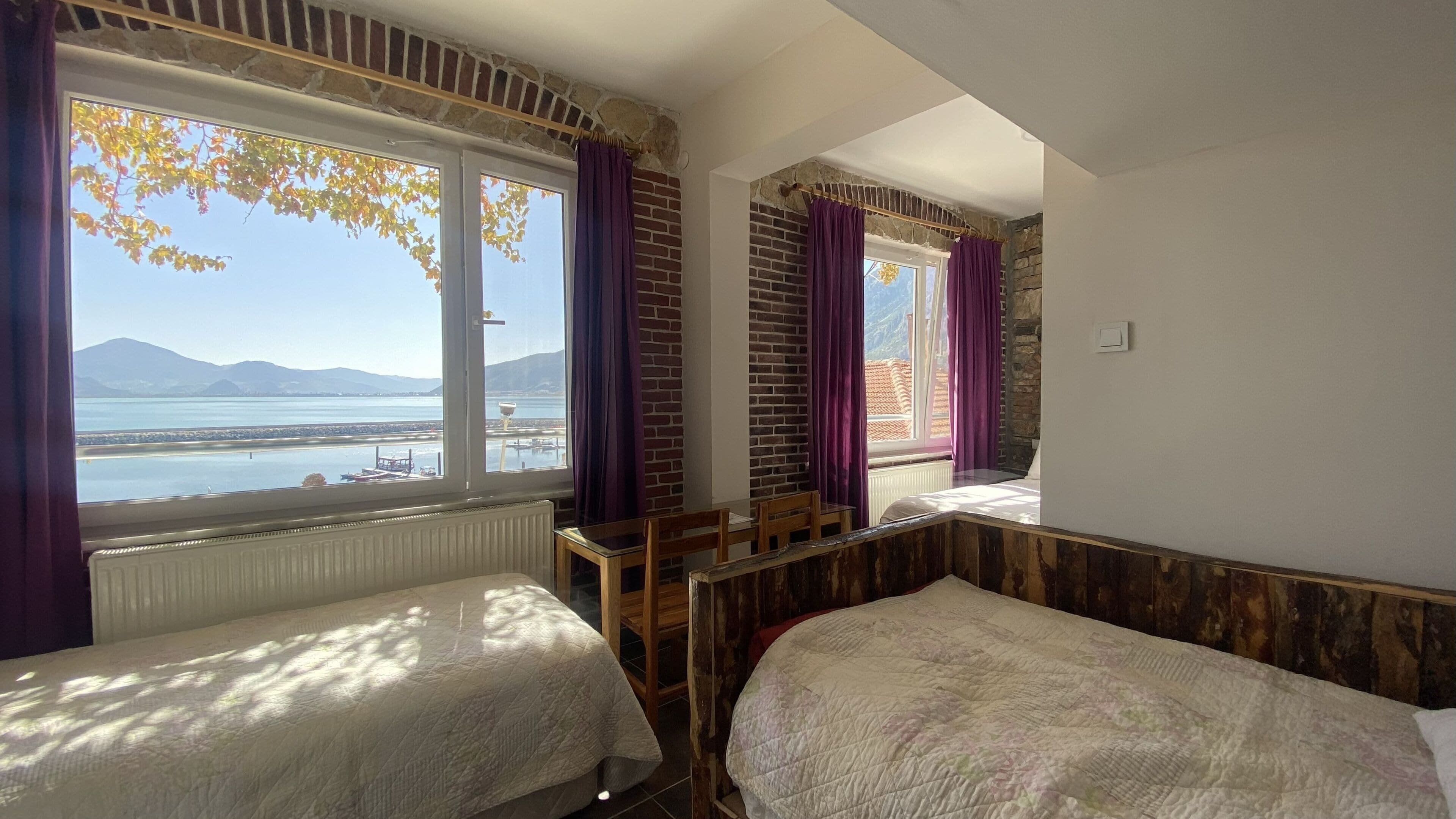 Quarto com duas camas, uma mesa e vista para o mar.