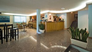 Um hall amplo com balcão de recepção, área de estar e escadaria.