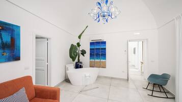 Uma sala de estar moderna com uma banheira branca, uma cadeira azul e uma planta grande.