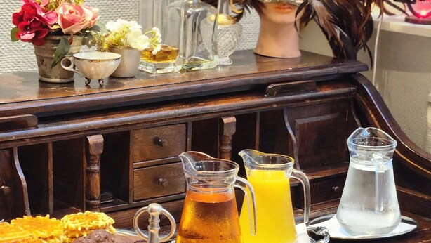 Buffet de café da manhã com waffles, pastelaria e jarra de suco de laranja.