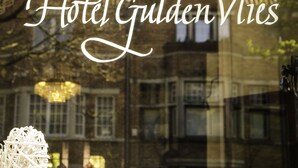 Uma janela com o texto "Hotel Gulden Vlies" e um emblema decorativo.