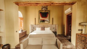 Um quarto espaçoso com uma cama grande, teto de madeira e um detalhe decorativo na parede.