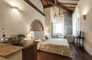 Quarto com cama, escrivaninha com luminária, cadeira e televisão.
