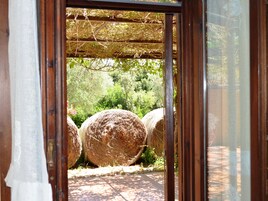 Uma entrada que dá para um jardim com fardos de feno e vegetação.