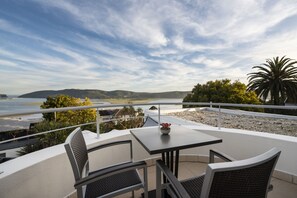 Varanda com mesa e cadeiras, oferecendo vista panorâmica de colinas e um corpo d'água.