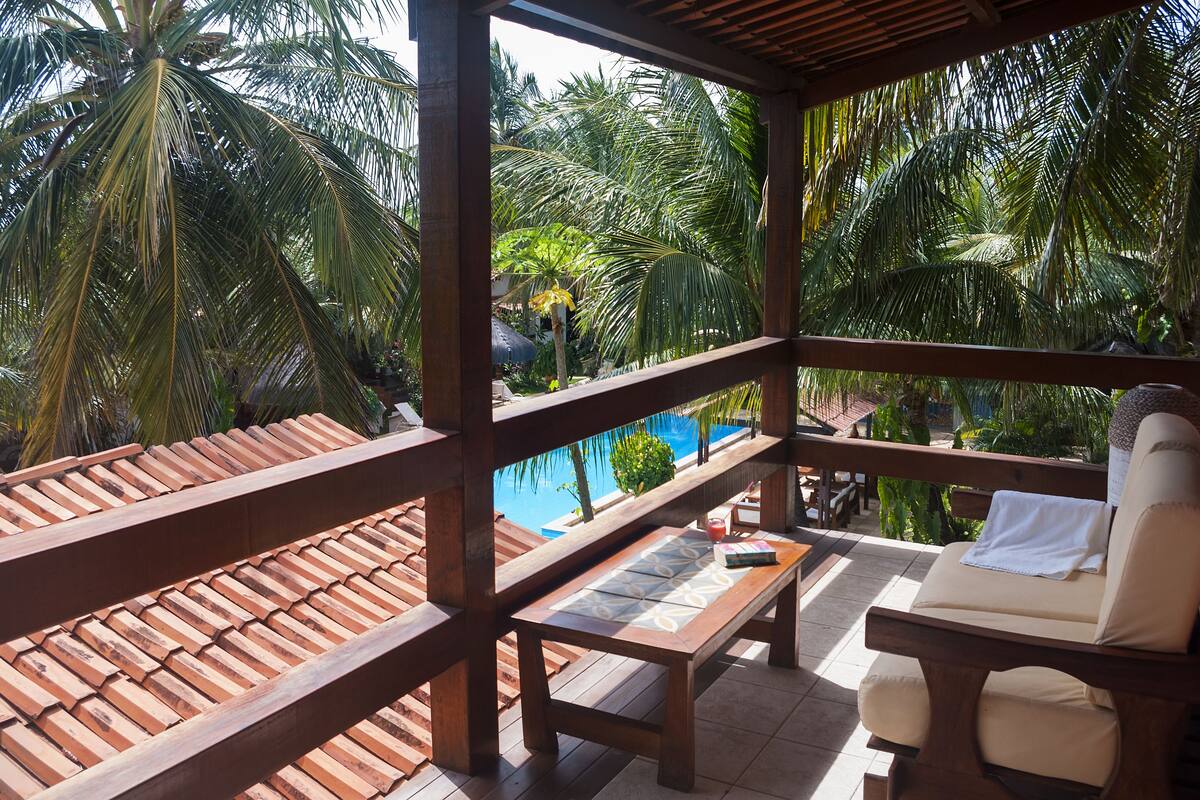 Um deck de madeira com vista para uma piscina e palmeiras.