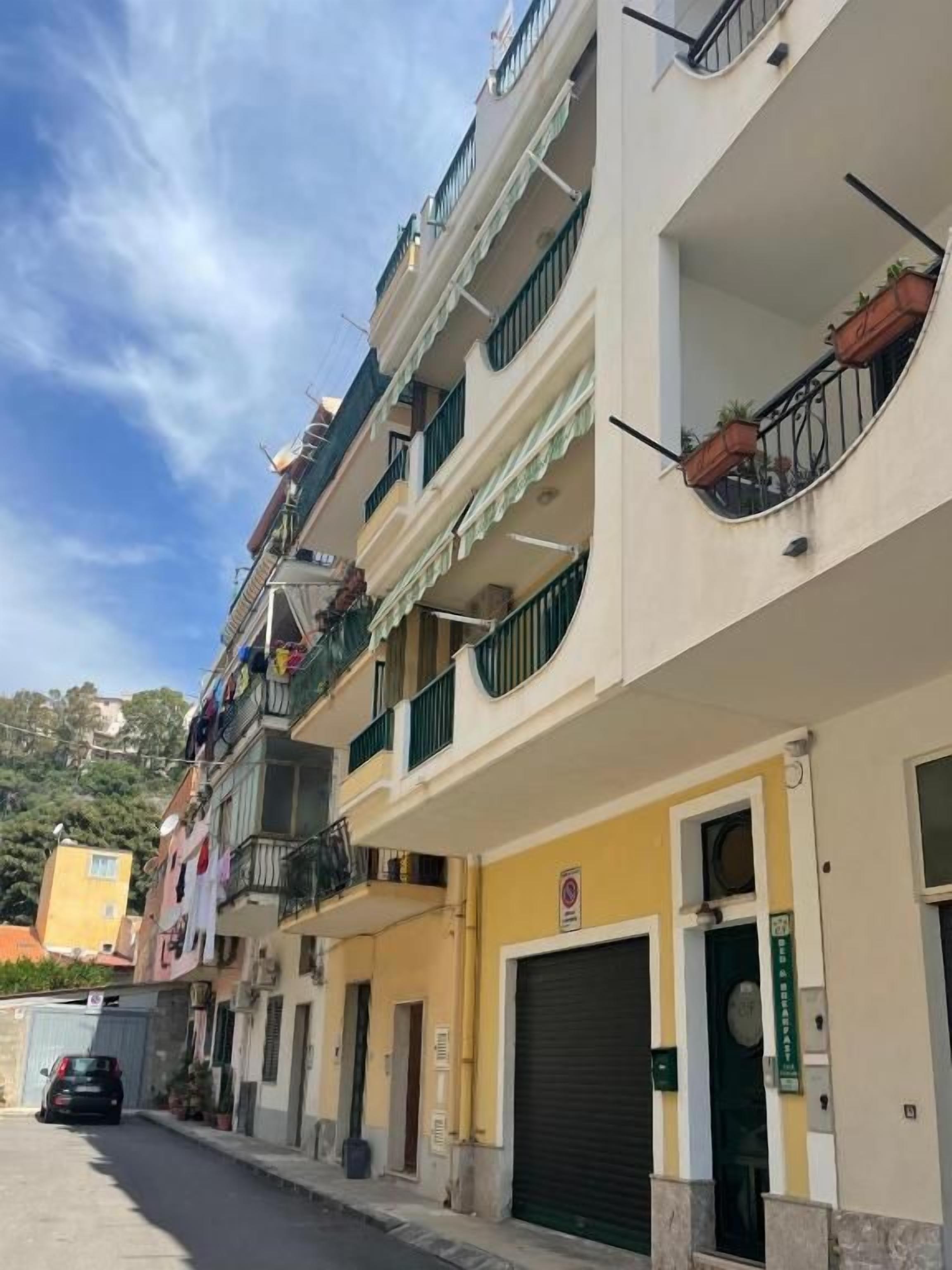Um edifício residencial com vários andares, varandas, uma porta de garagem e céu claro.