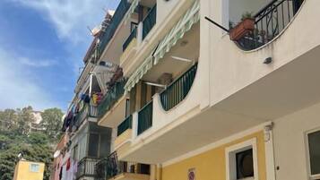 Um edifício residencial com vários andares, varandas, uma porta de garagem e céu claro.