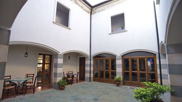 Um pátio com piso de azulejos, móveis de madeira e plantas em vasos.