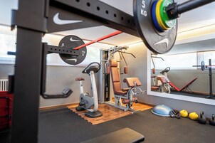 Academia com equipamentos de exercícios, espelho e janela.