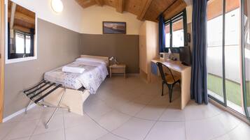 Um quarto com cama, escrivaninha, cadeira, mesa pequena e janela com cortinas.