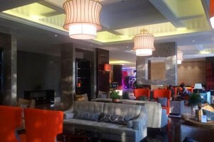 Um hall de hotel com sofá, cadeiras e balcão de recepção.