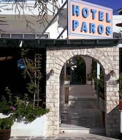Entrada de hotel com arco de pedra e placa com a inscrição 'HOTEL PAROS'.