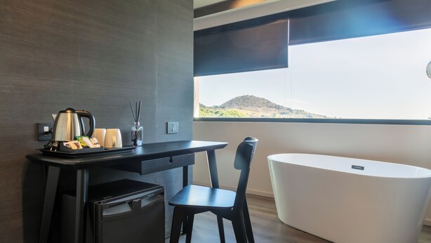 Quarto moderno com escrivaninha, cadeira e banheira branca.