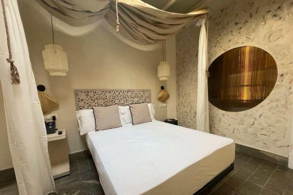 Quarto com uma cama grande, um espelho redondo e uma parede texturizada.