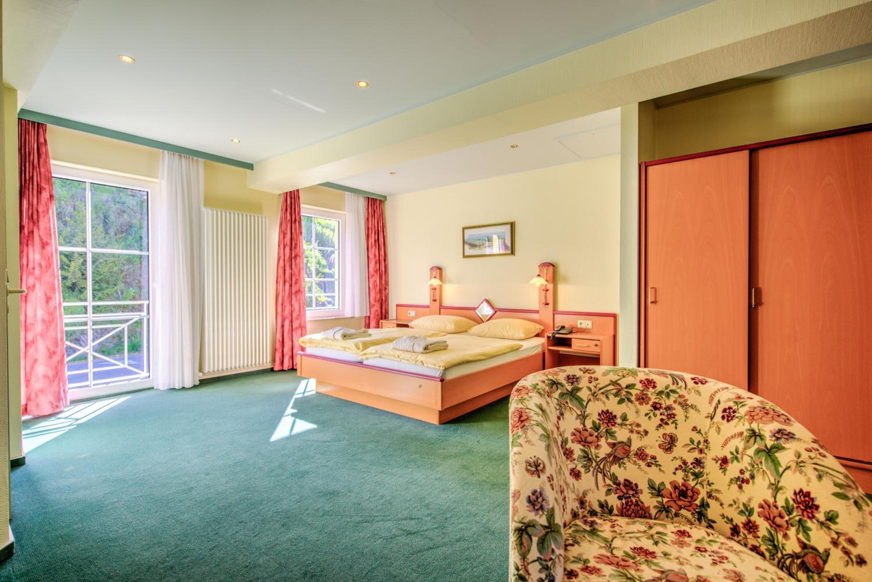 Quarto com cama, cadeira, guarda-roupa e janela com cortinas.