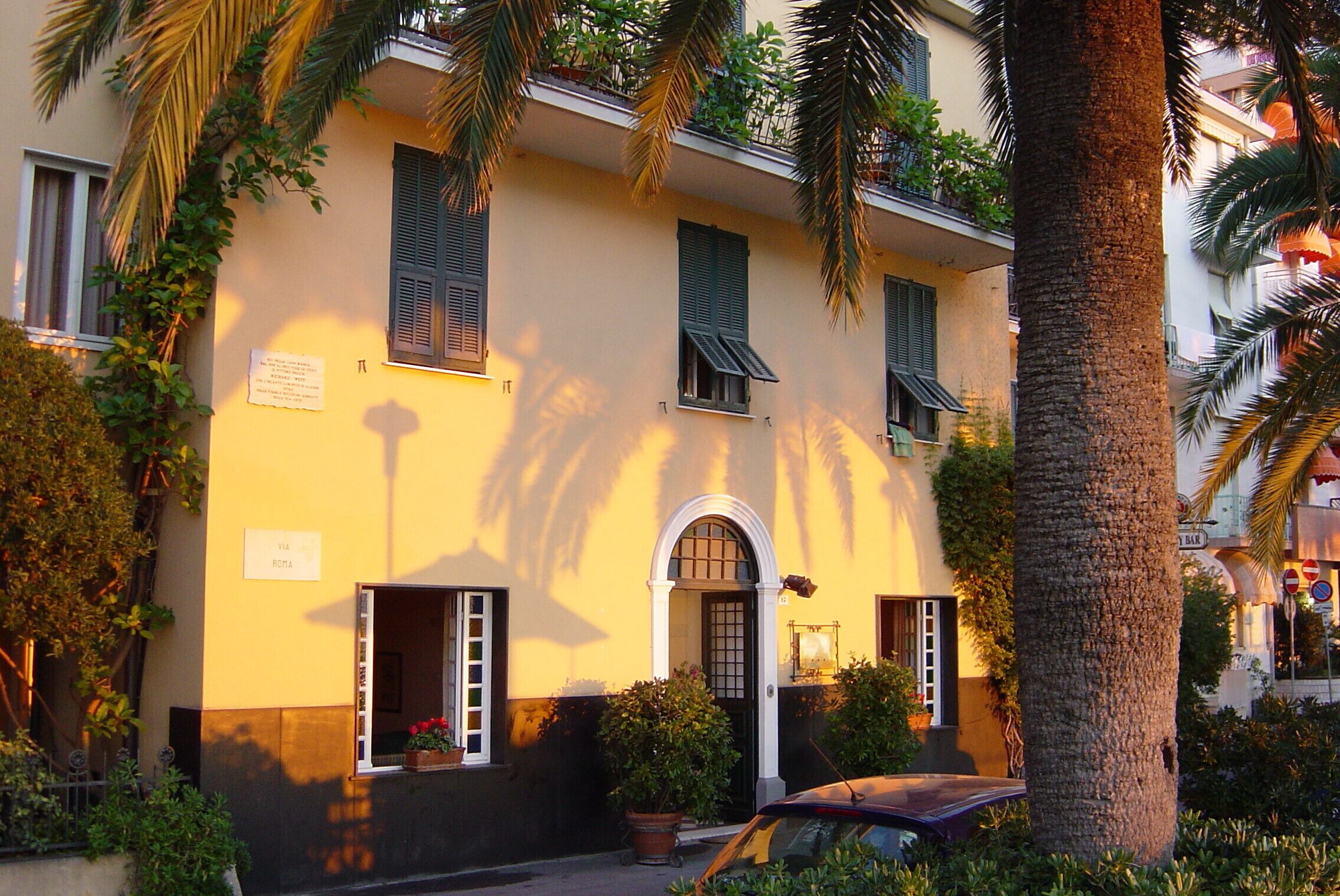 Um edifício com fachada amarela, toldo preto e uma porta com janela acima.