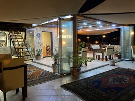 Um interior moderno com divisória de vidro, escada e sala de jantar com cadeiras e mesas.