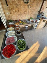Buffet com diversos alimentos, incluindo fatias de tomate, pepino e carnes.