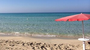 Uma praia com águas azuis cristalinas e um guarda-sol vermelho.