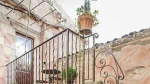 Uma escadaria de pedra com guarda-corpo de ferro forjado que leva a uma varanda.