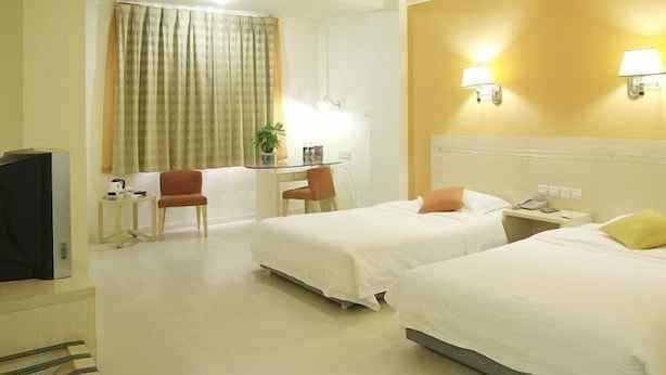Quarto de hotel com duas camas, uma escrivaninha, uma cadeira, uma televisão e um abajur.