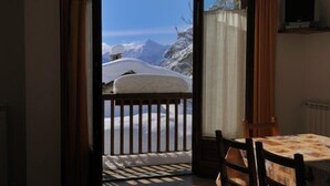 Quarto com vista para montanhas cobertas de neve através de uma porta aberta.
