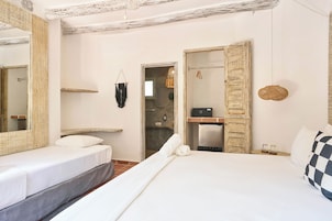 Quarto de hotel com duas camas, um espelho grande, um guarda-roupa e um banheiro visível por uma porta aberta.