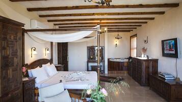 Quarto de hotel com uma cama grande, móveis de madeira, um candelabro e uma TV de tela plana.