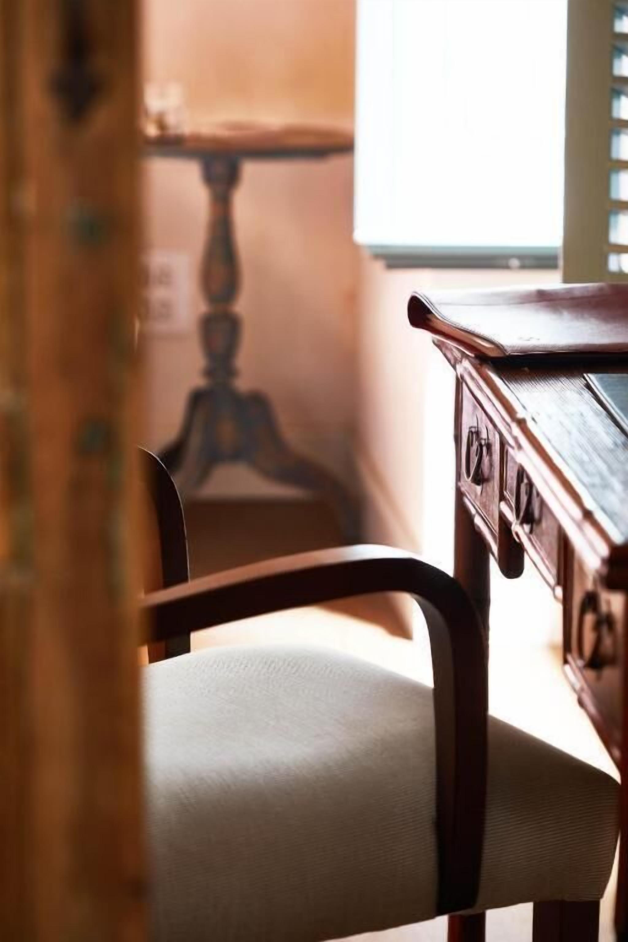 Uma mesa de madeira com gavetas e uma cadeira em frente.