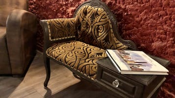 Um sofá de estilo antigo com padrões elaborados, uma poltrona a combinar e uma mesa de centro com uma revista.