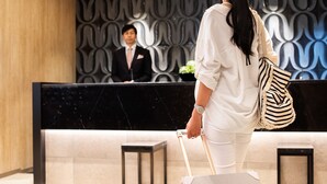 Uma área de recepção de hotel com design moderno, incluindo uma parede estampada e um balcão de atendimento.