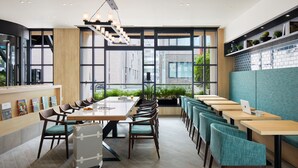 Restaurante moderno com uma mesa comunitária grande, cabines individuais e vista da cidade através de janelas amplas.