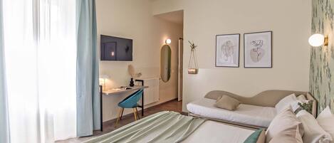 Quarto de hotel com uma cama grande, uma escrivaninha com cadeira, um pequeno sofá e obras de arte nas paredes.