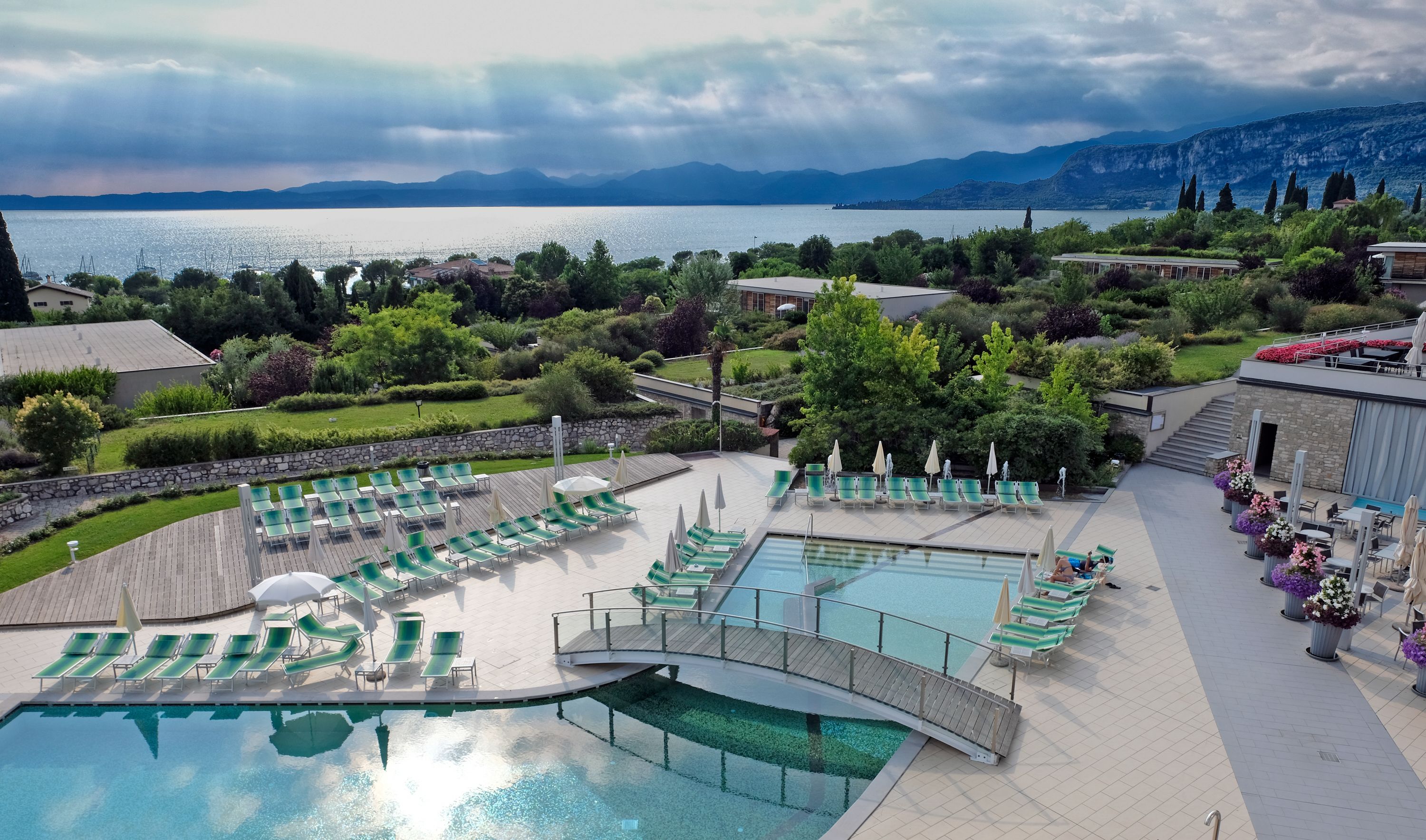 Um resort com piscina, espreguiçadeiras e vista para o lago.