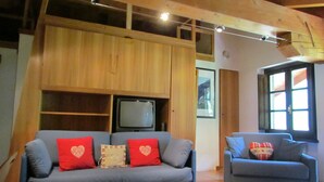 Uma sala de estar acolhedora com dois sofás, uma televisão e painéis de madeira.