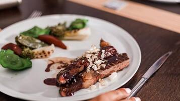 Um prato com bife, legumes e molho.
