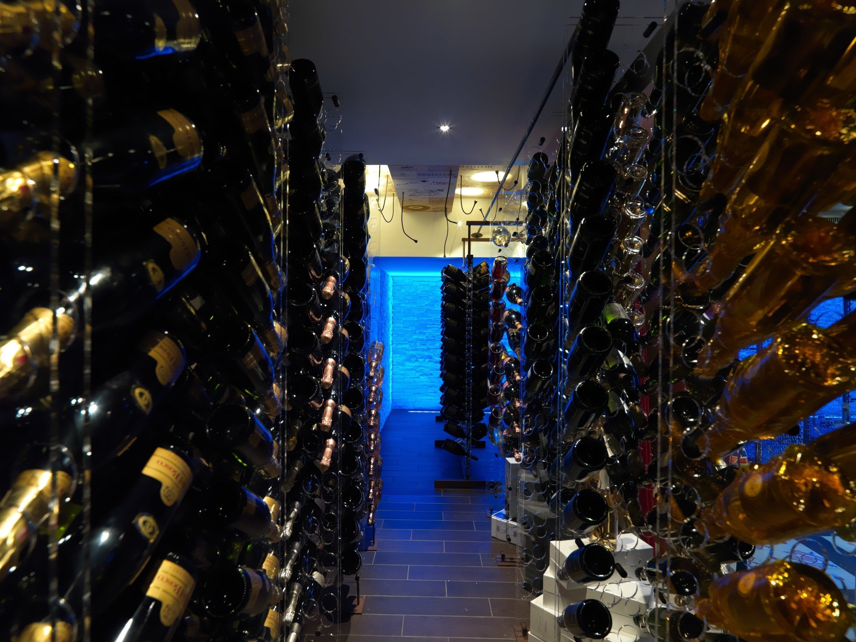Uma adega com fileiras de garrafas de vinho e copos em prateleiras.