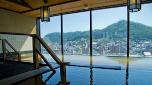 Piscina interior com vista para a paisagem urbana e montanhas.