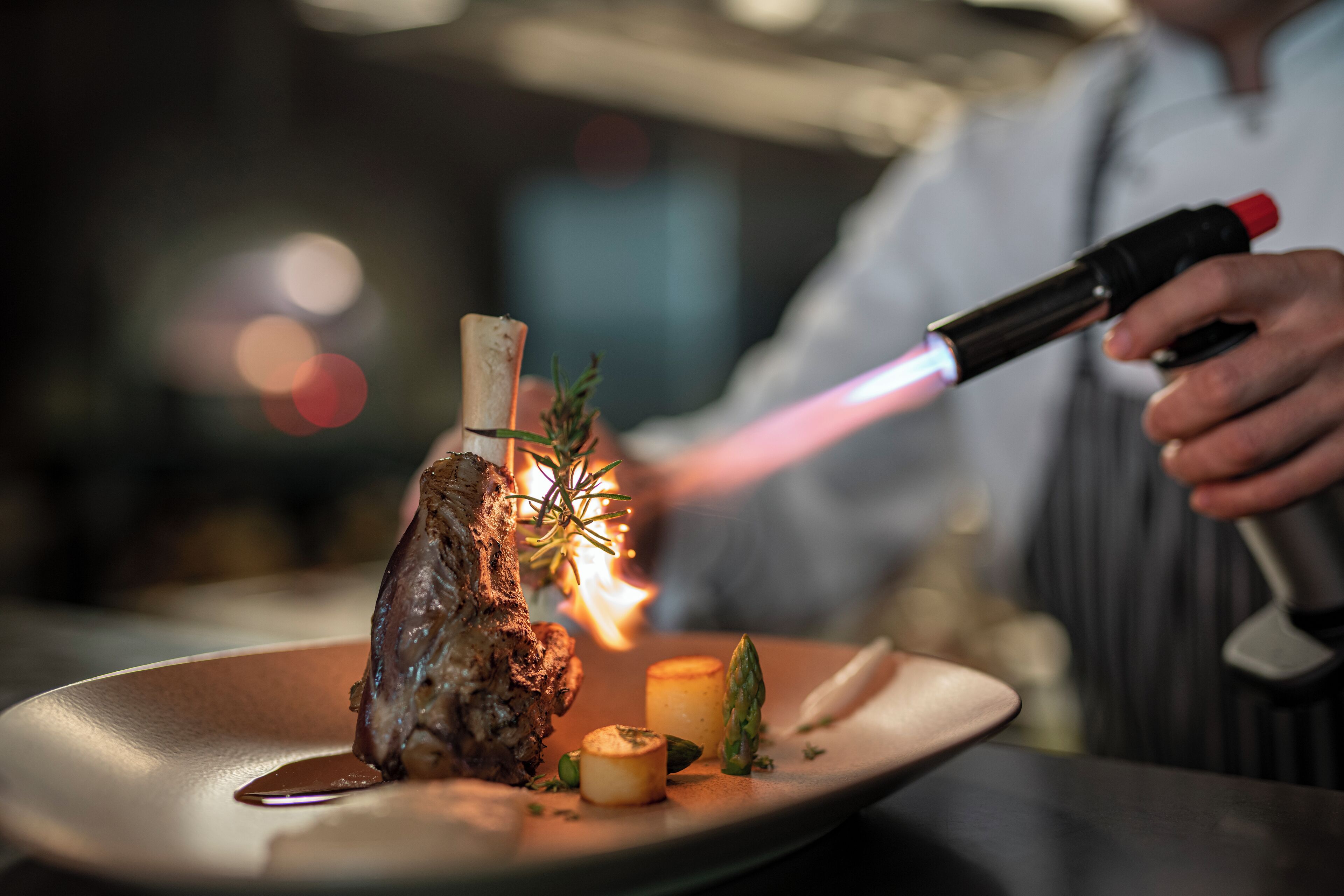Um chef preparando um bife com um maçarico.