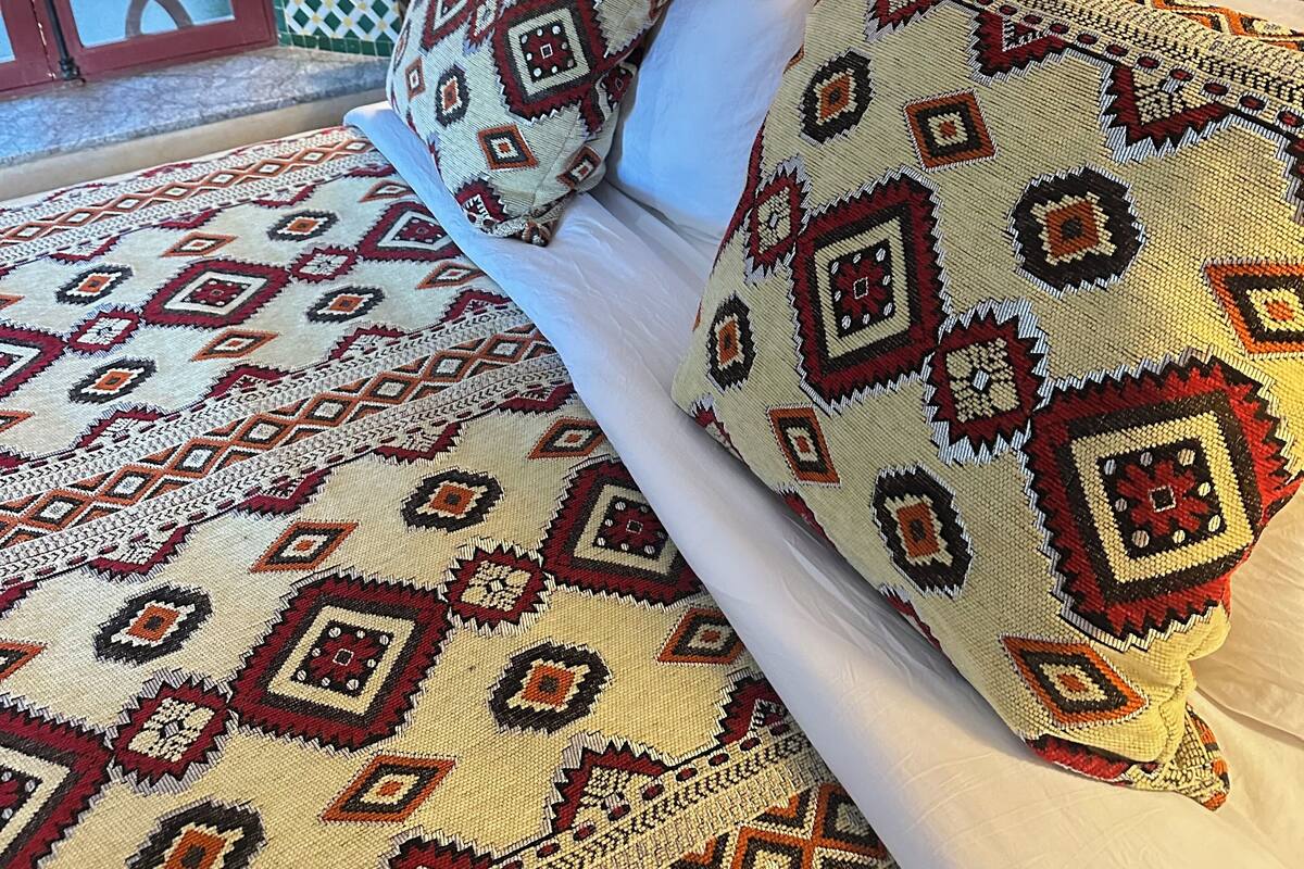 Uma cama com roupa de cama estampada e um detalhe decorativo na parede.