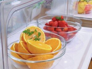 Uma taça de vidro com fatias de laranja e uma tigela à parte com morangos.