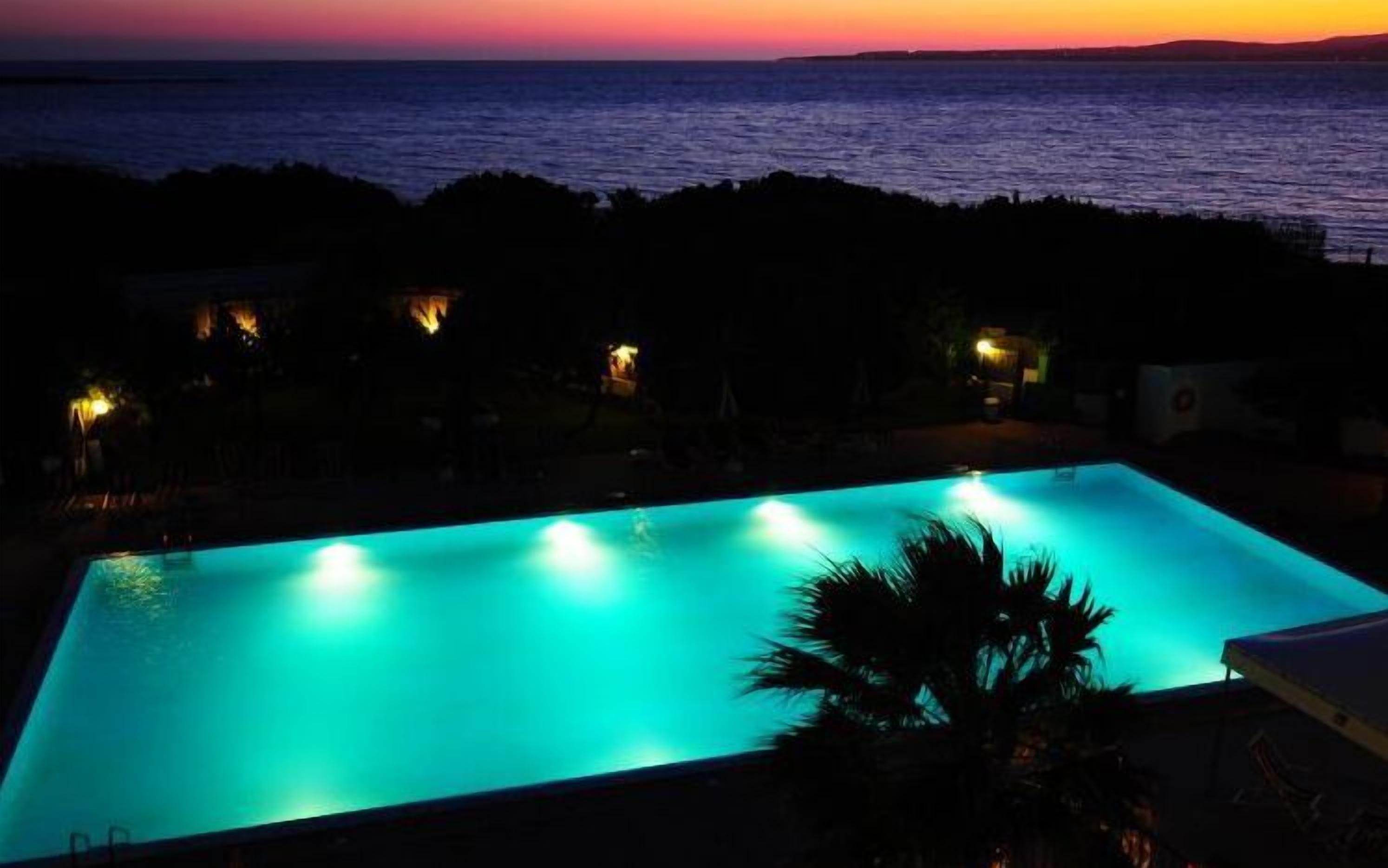 Piscina ao anoitecer com vista para o oceano.
