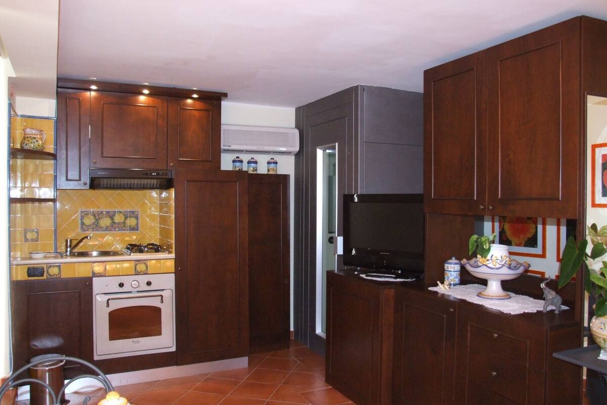 Cozinha compacta com armários de madeira, fogão e micro-ondas.