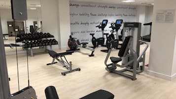 Uma academia com diversos equipamentos de exercício, incluindo halteres, esteiras e aparelhos de musculação.